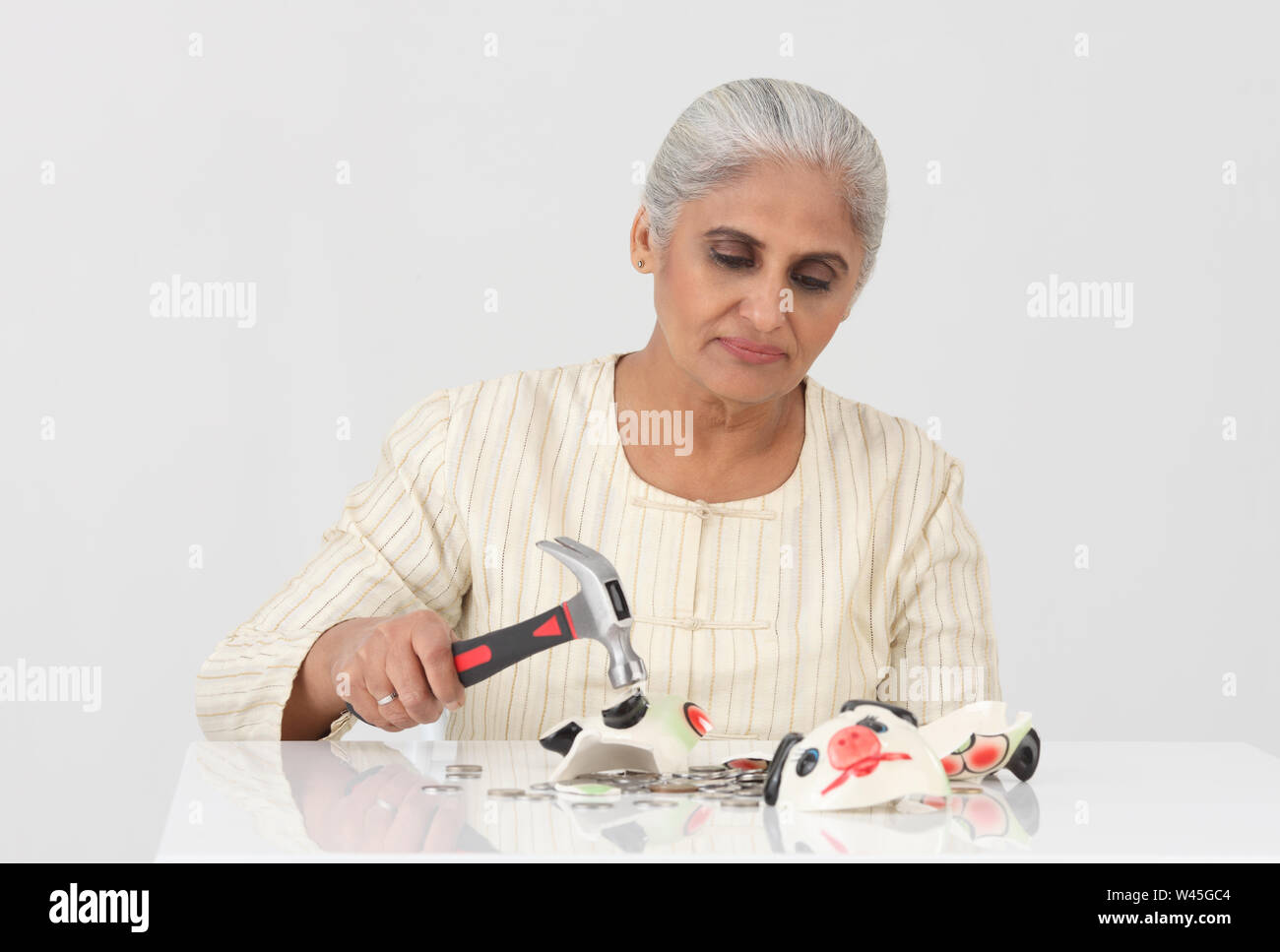 Woman using hammer to smash a piggybank Stock Photo - Alamy
