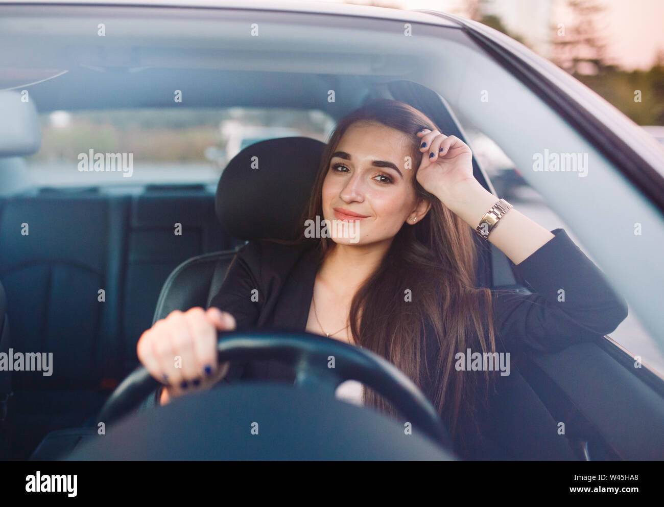 Cute brunette girl in the car. Elegant business woman driving a car ...