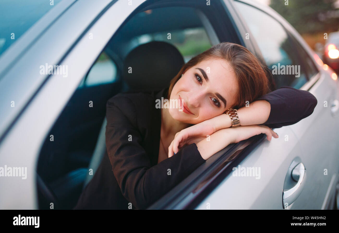 Cute brunette girl in the car. Elegant business woman driving a car ...