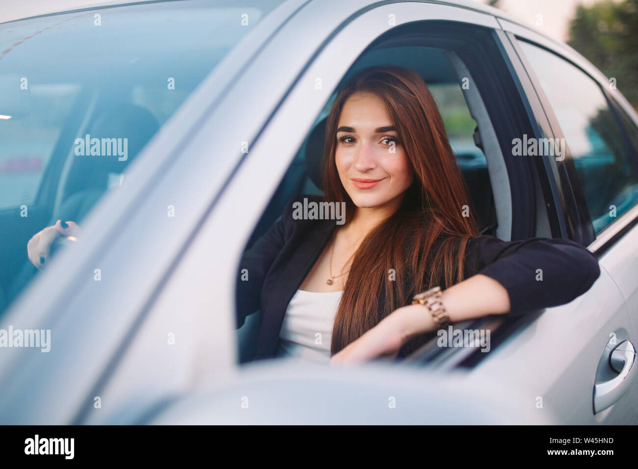Cute brunette girl in the car. Elegant business woman driving a car ...