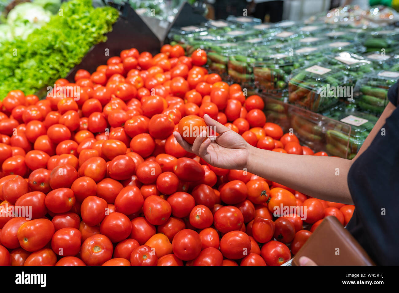 Asian woman buying and picking fresh tomato at grocery store Stock ...