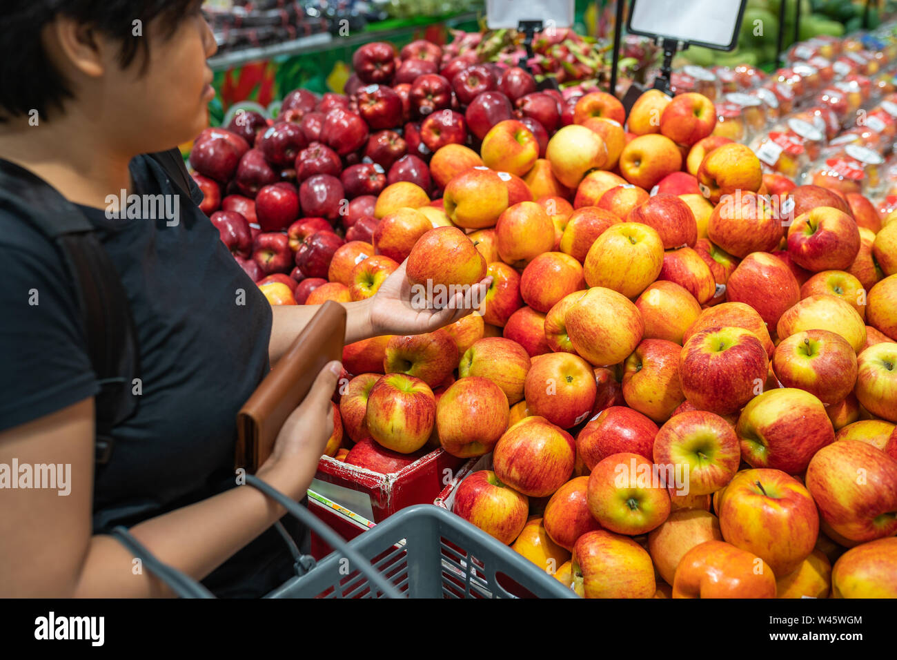 Asian woman picking apple at fruit stand in grocery store Stock Photo ...