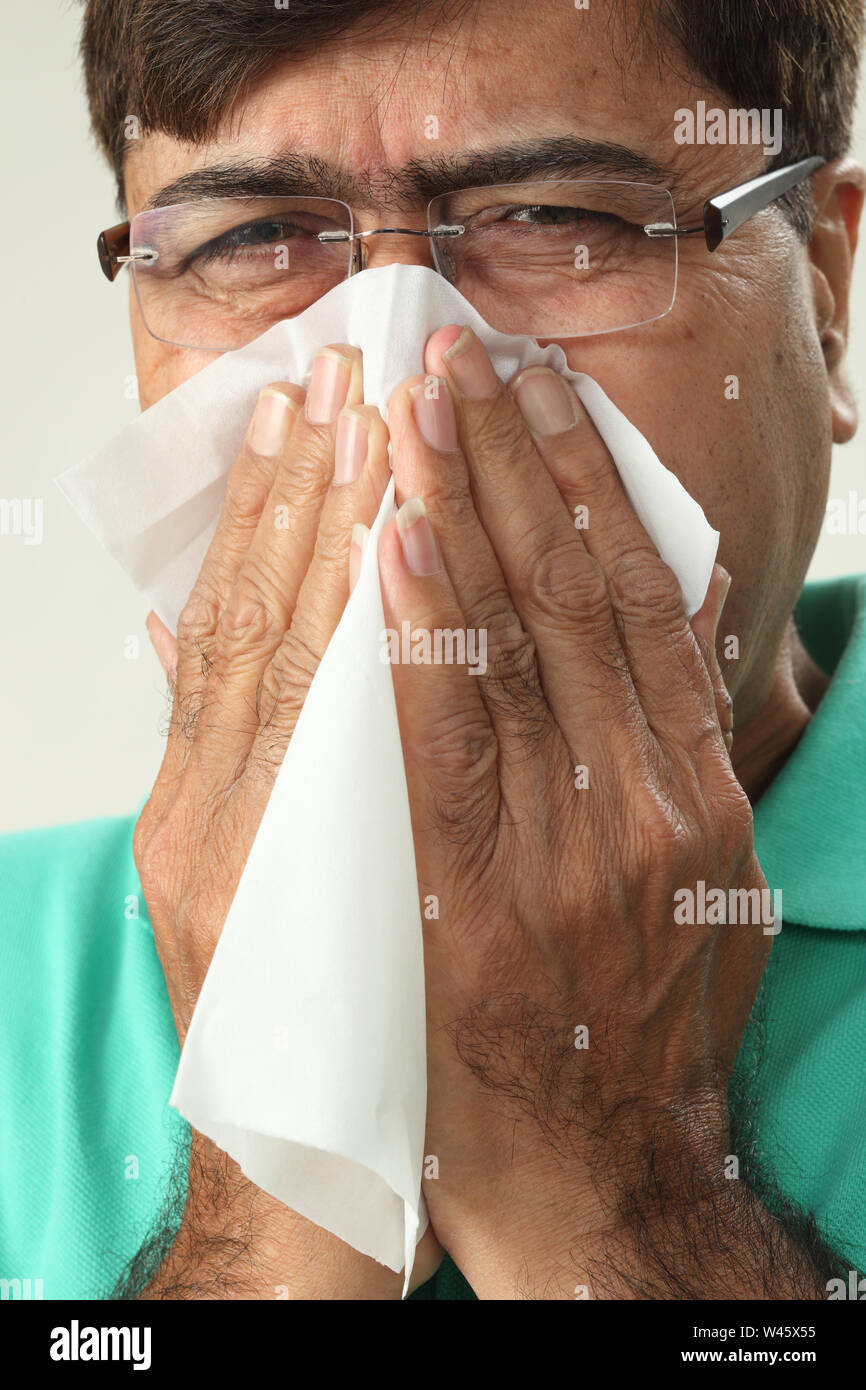 Man blowing nose with tissue paper Stock Photo - Alamy
