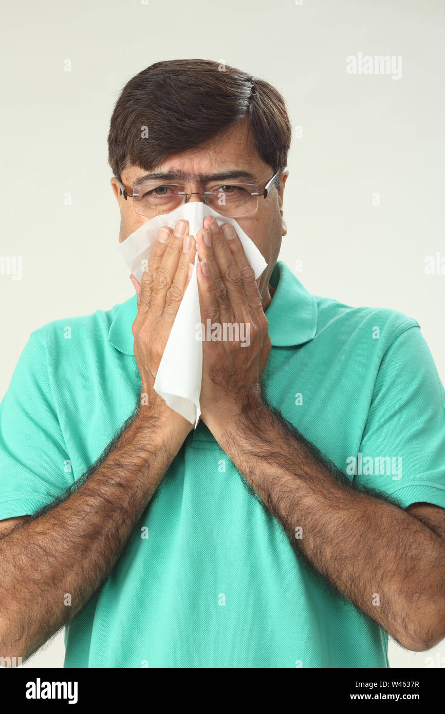 Man blowing nose with tissue paper Stock Photo - Alamy