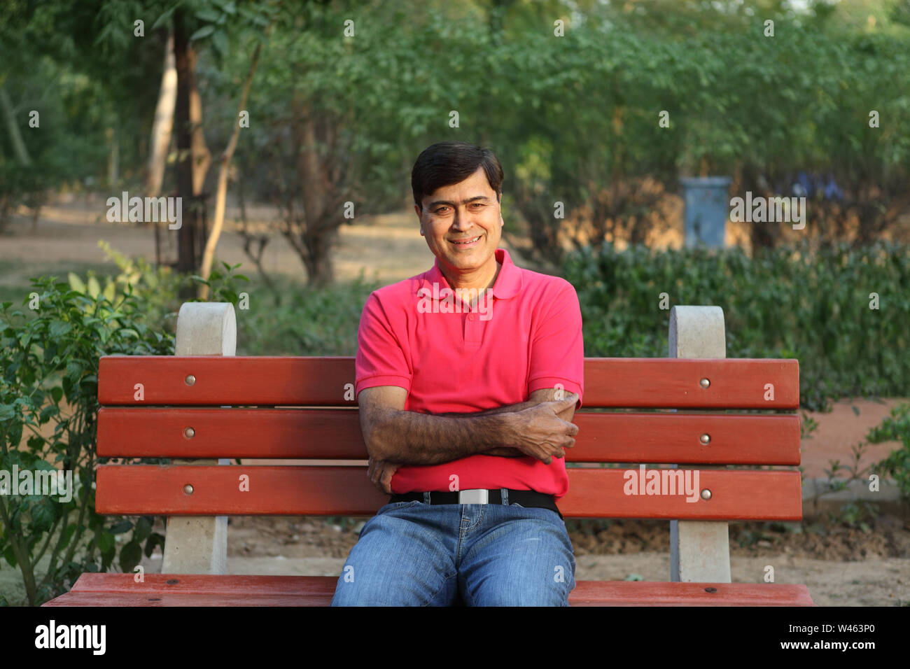 Man sitting on a park bench and smiling Stock Photo - Alamy