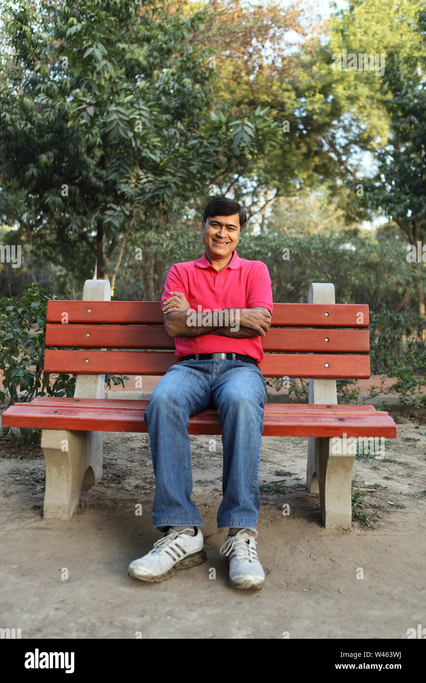 Man sitting on a park bench and smiling Stock Photo - Alamy