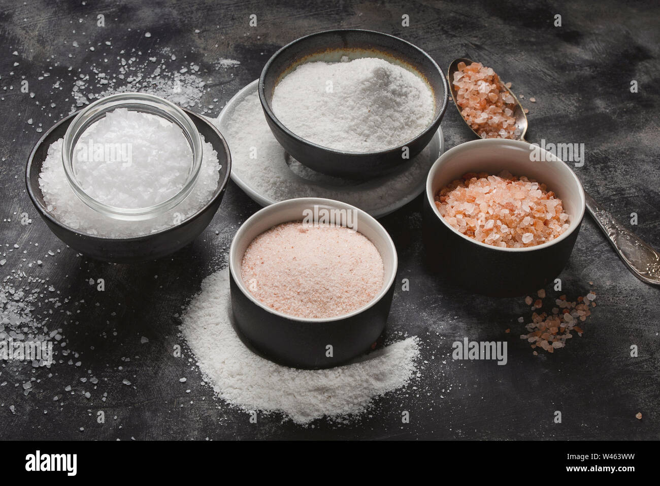 Different types of salt on black background Stock Photo - Alamy