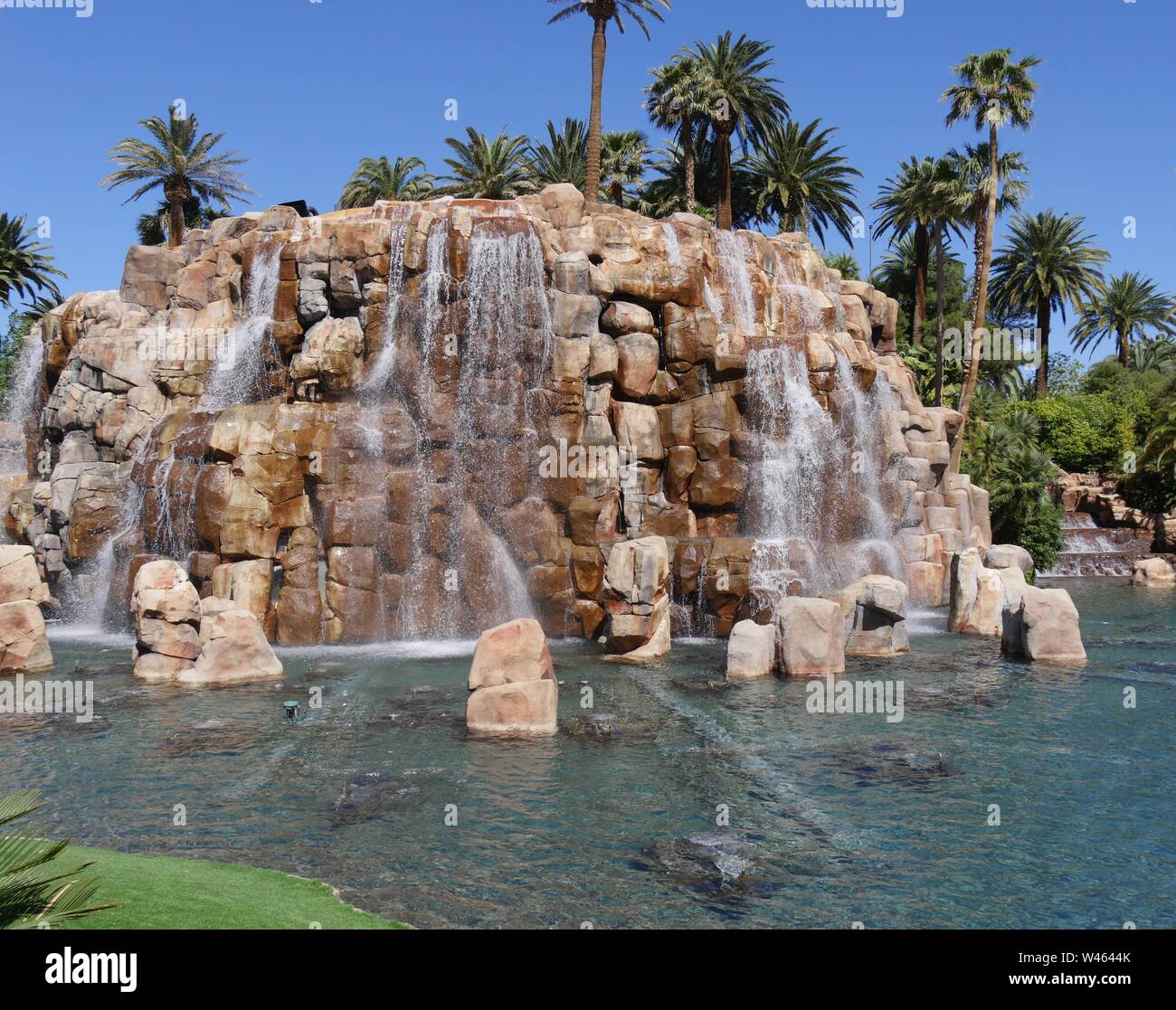 Wide shot of a waterfalls in a beautifully-landscaped garden with palm ...