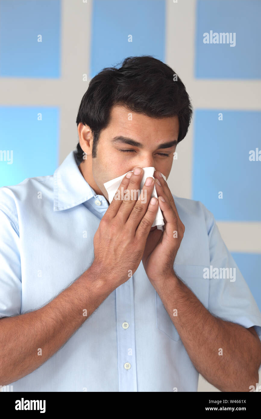Man blowing nose with tissue paper Stock Photo - Alamy