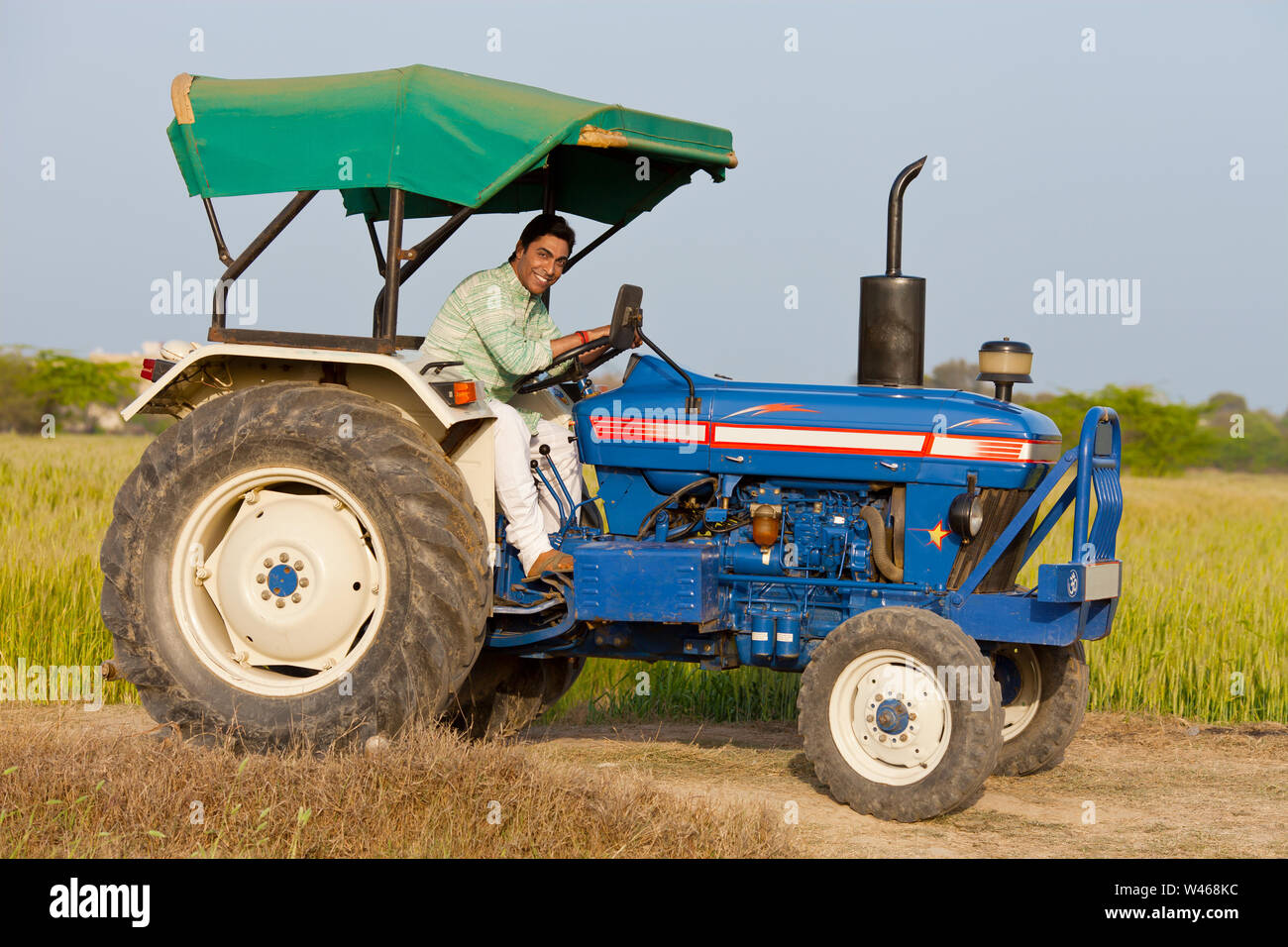 Farmer driving a tractor in a field Stock Photo - Alamy