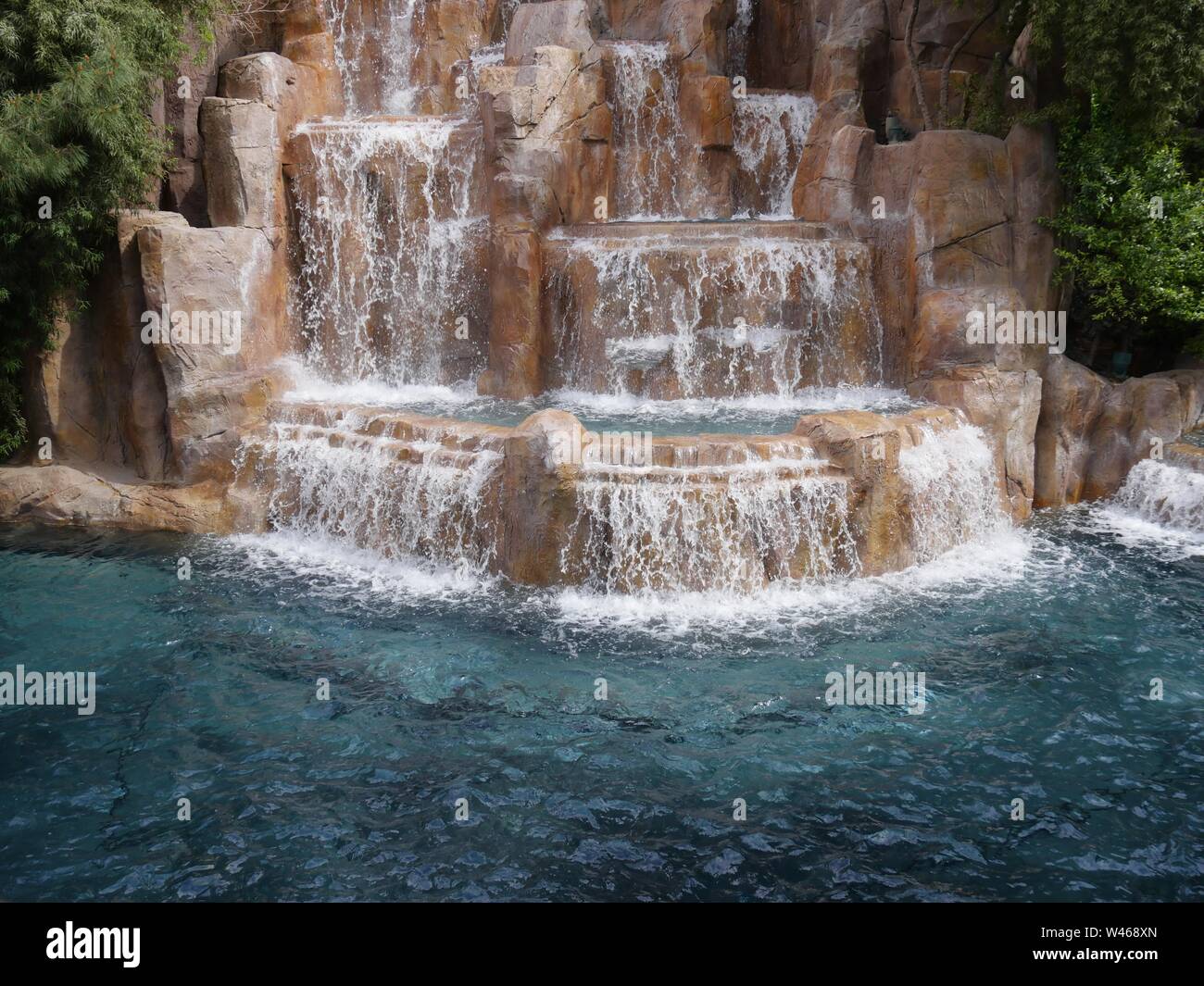 Clear water forms into a pool flowing down a man-made waterfalls Stock ...