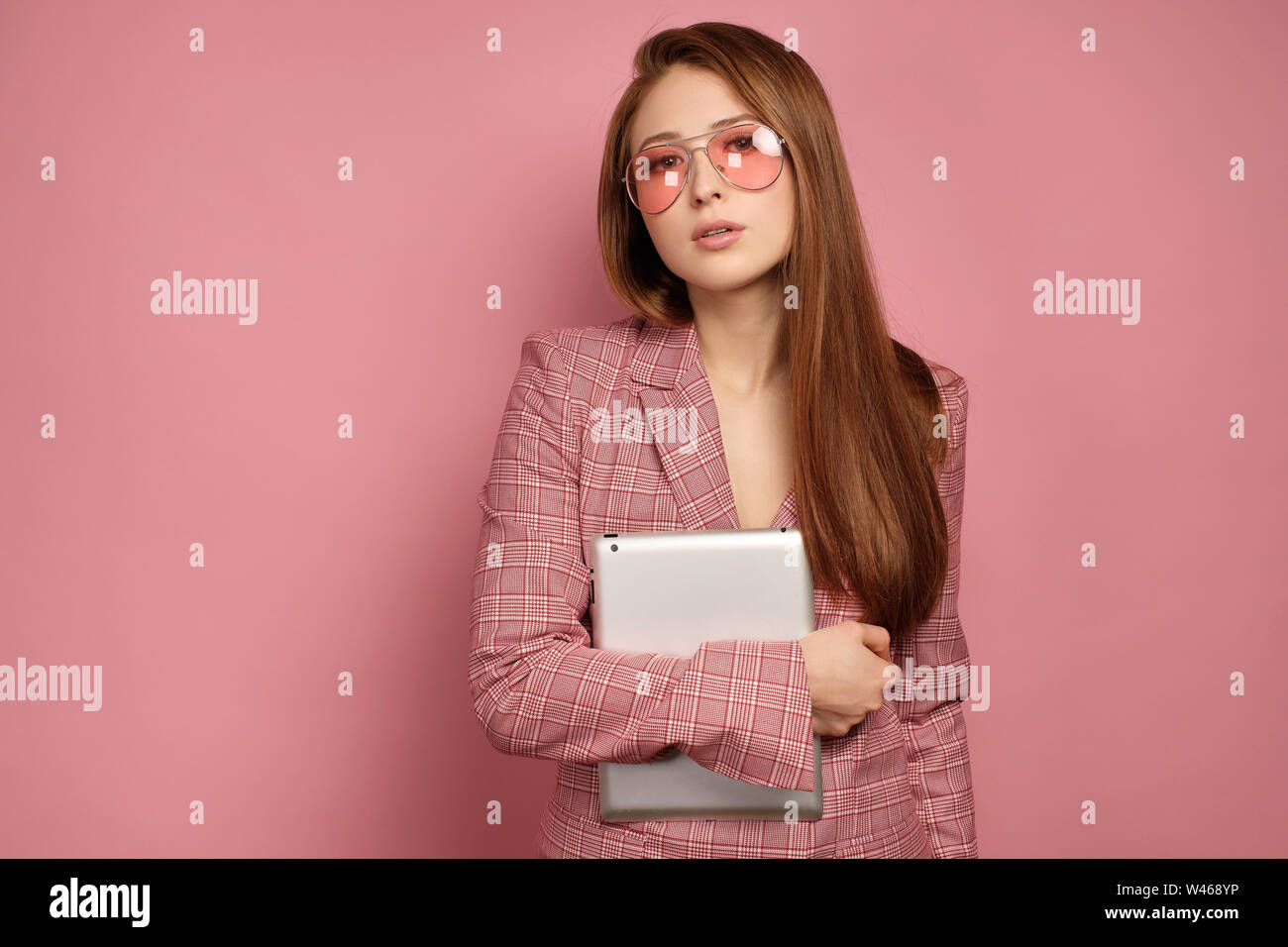 Young woman looks at the camera calmly through pink eye glasses over ...