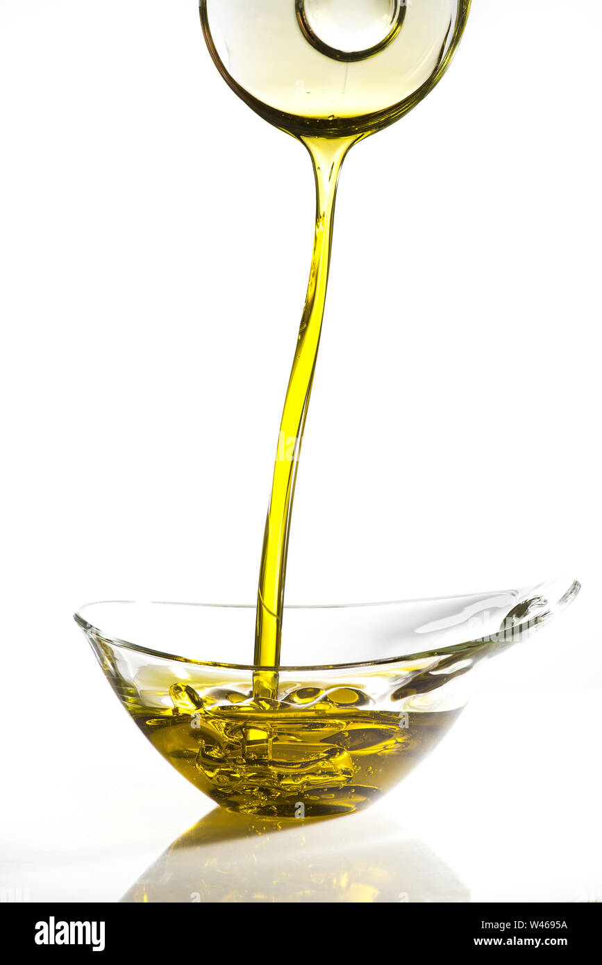 in a transparent crystal bowl flows extra virgin olive oil poured from ...