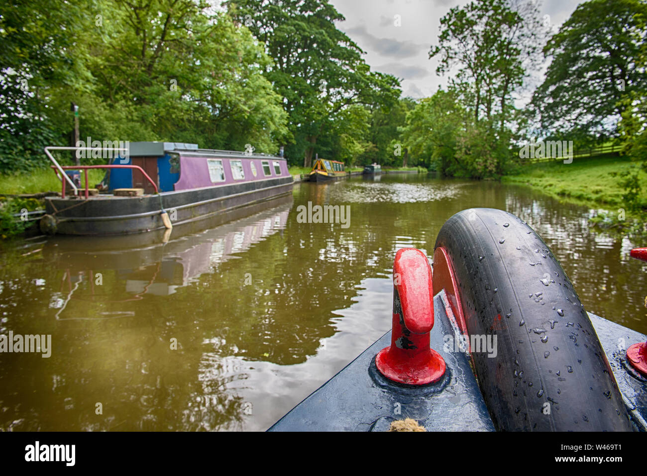 View from the bow of boat with narrowboats moored up in English rural ...