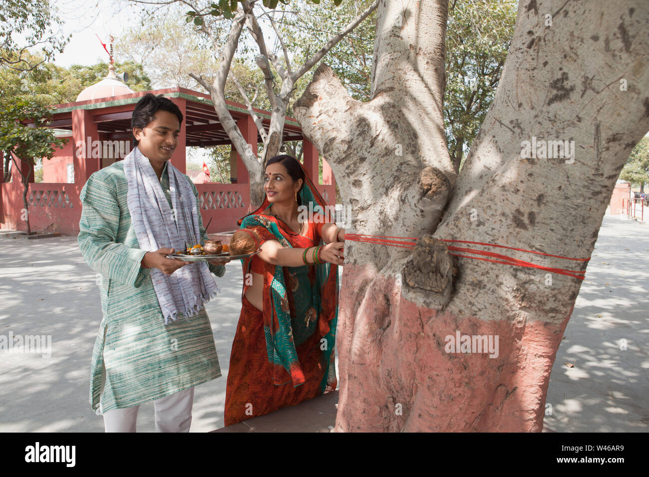 Woman tying thread around a sacred tree with her husband Stock Photo ...