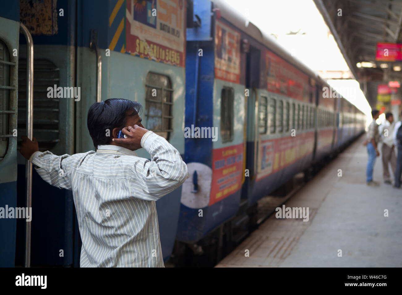 Passenger talking on mobile phone at a railway station Stock Photo - Alamy