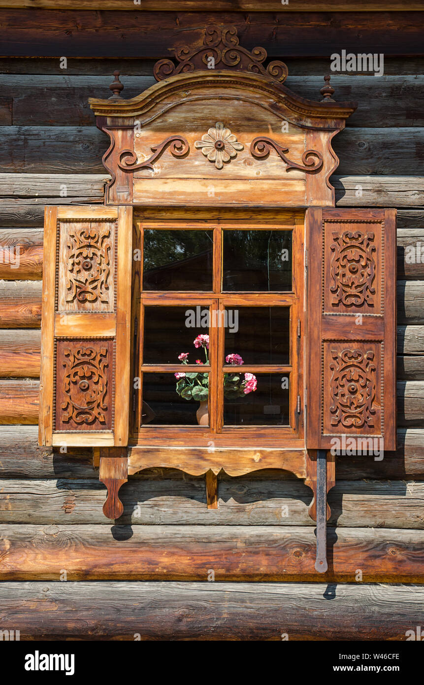 The window with the wooden carved architrave in the old wooden house in ...