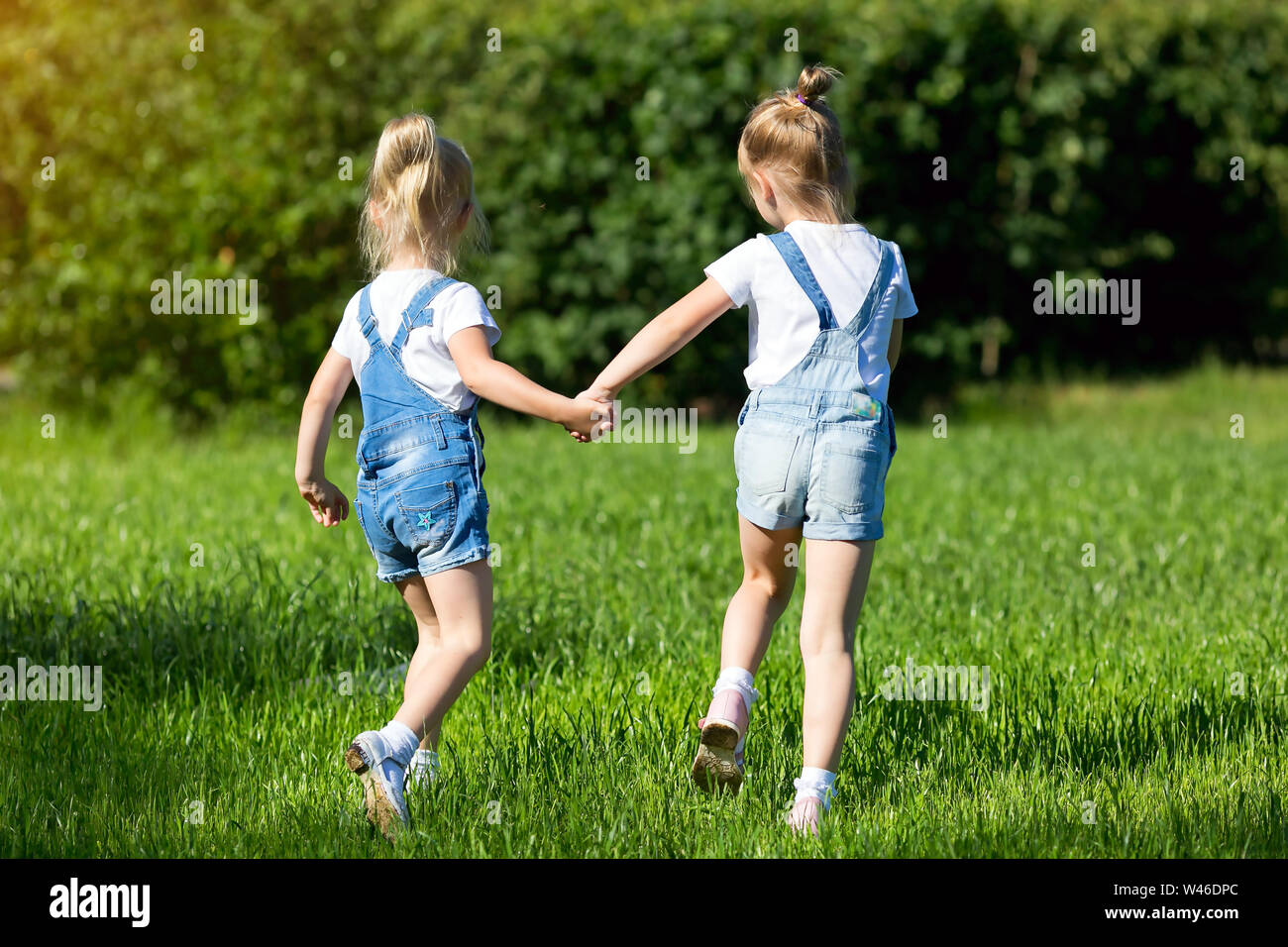 Girls running around the lawn with grass playing with splashes of water ...