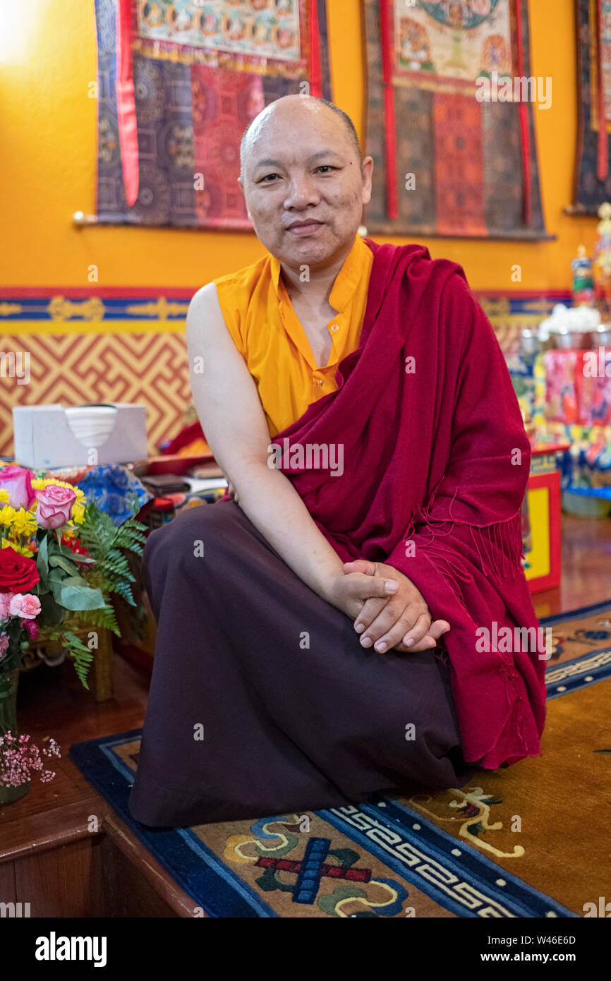 Posed portrait of a Sherpa Nepalese Buddhist monk in burgundy robes. At ...