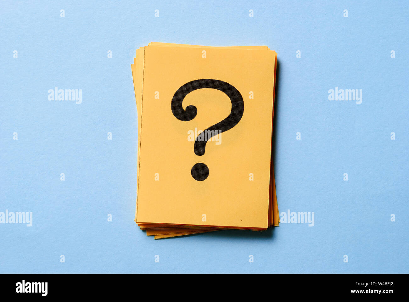 Stack of question marks on yellow cards arranged to the side on blue ...