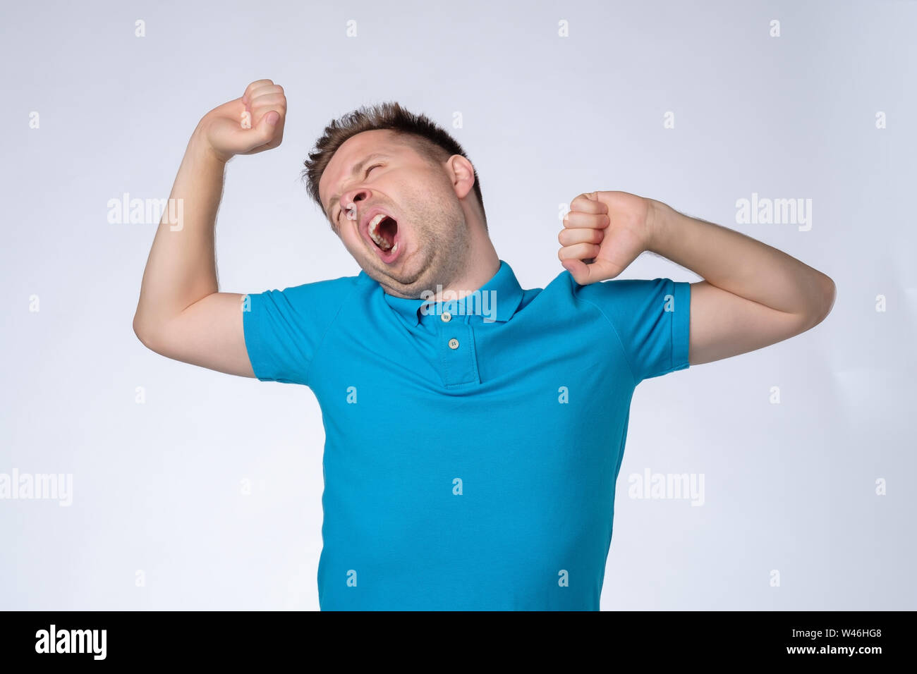 Tired european man in blue shirt feels sleepy, yawns as feels tired ...