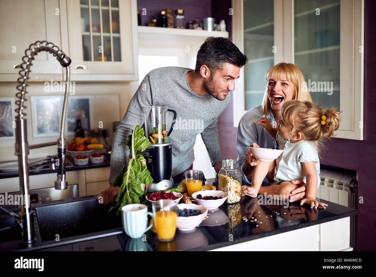 Family with child in kitchen having breakfast Stock Photo - Alamy