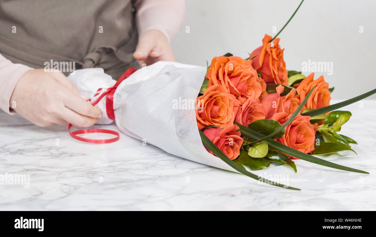 Florist wrapping red roses into a beautiful bouquet Stock Photo - Alamy