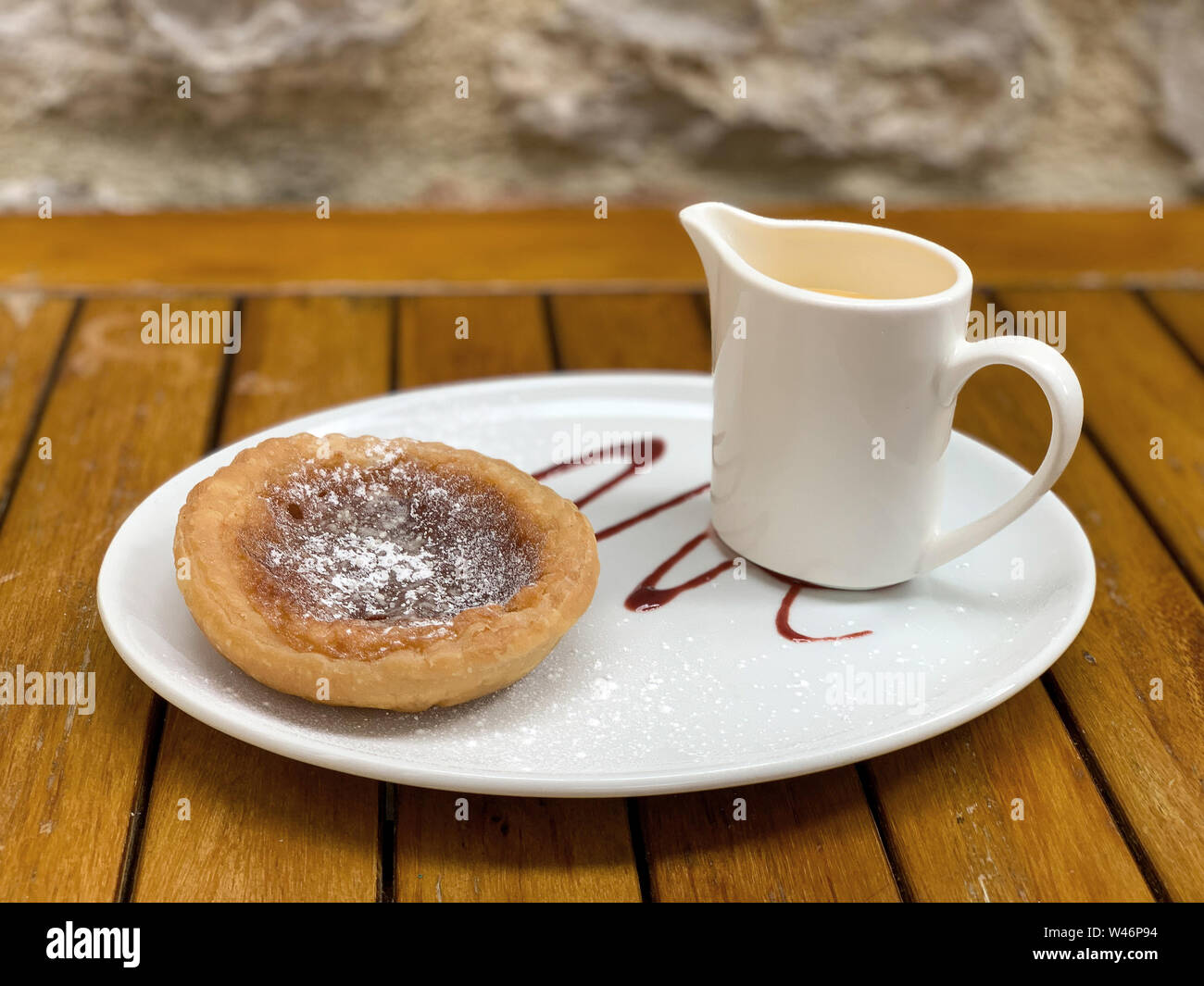 Traditional Bakewell pudding with a jug of custard Stock Photo - Alamy