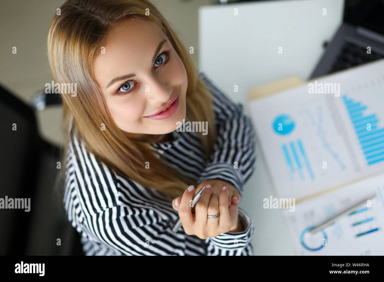 Beautiful smiling clerk sitting at working table Stock Photo - Alamy