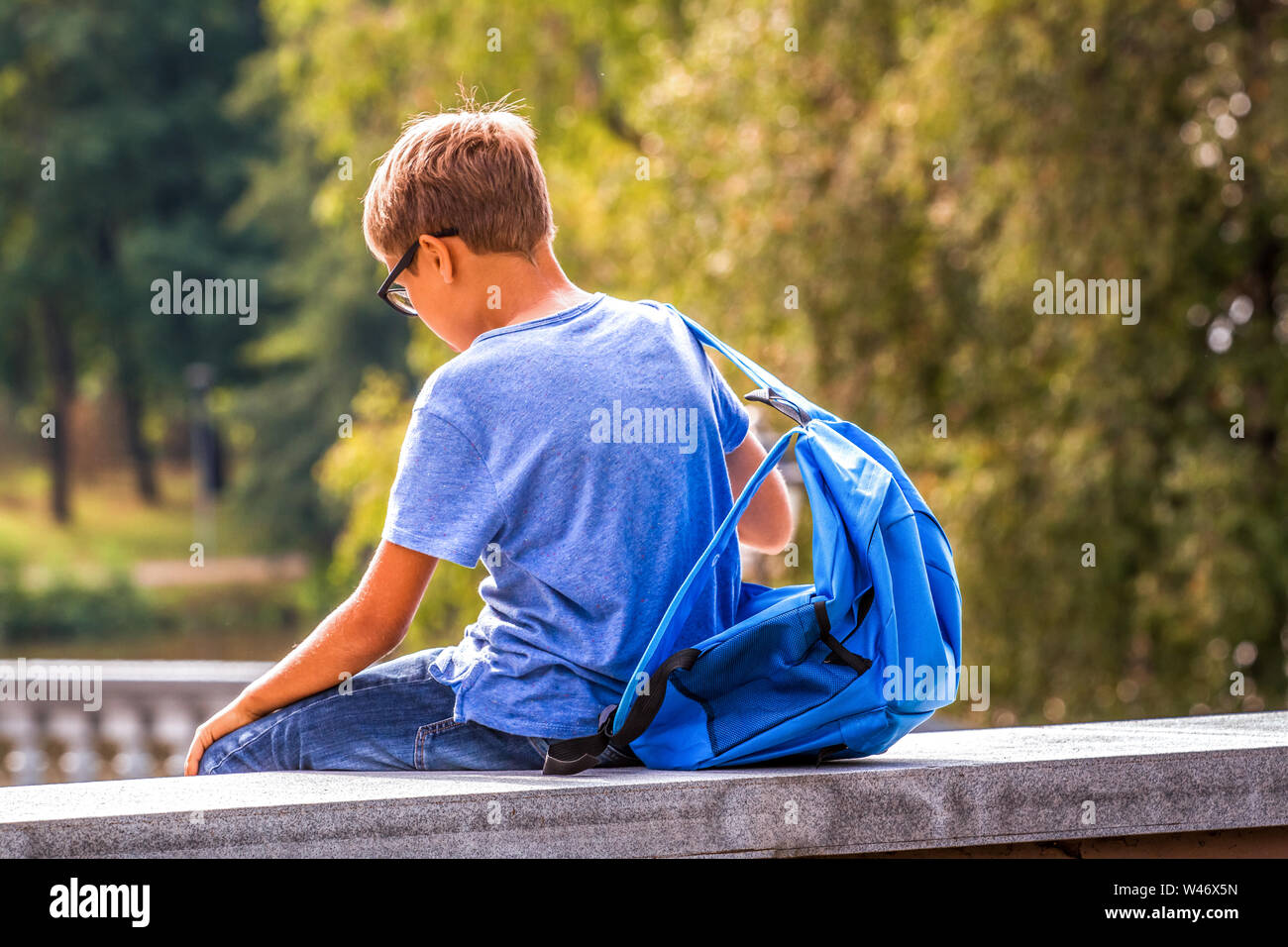 Tired kid with backpack sitting outdoors after school Stock Photo - Alamy