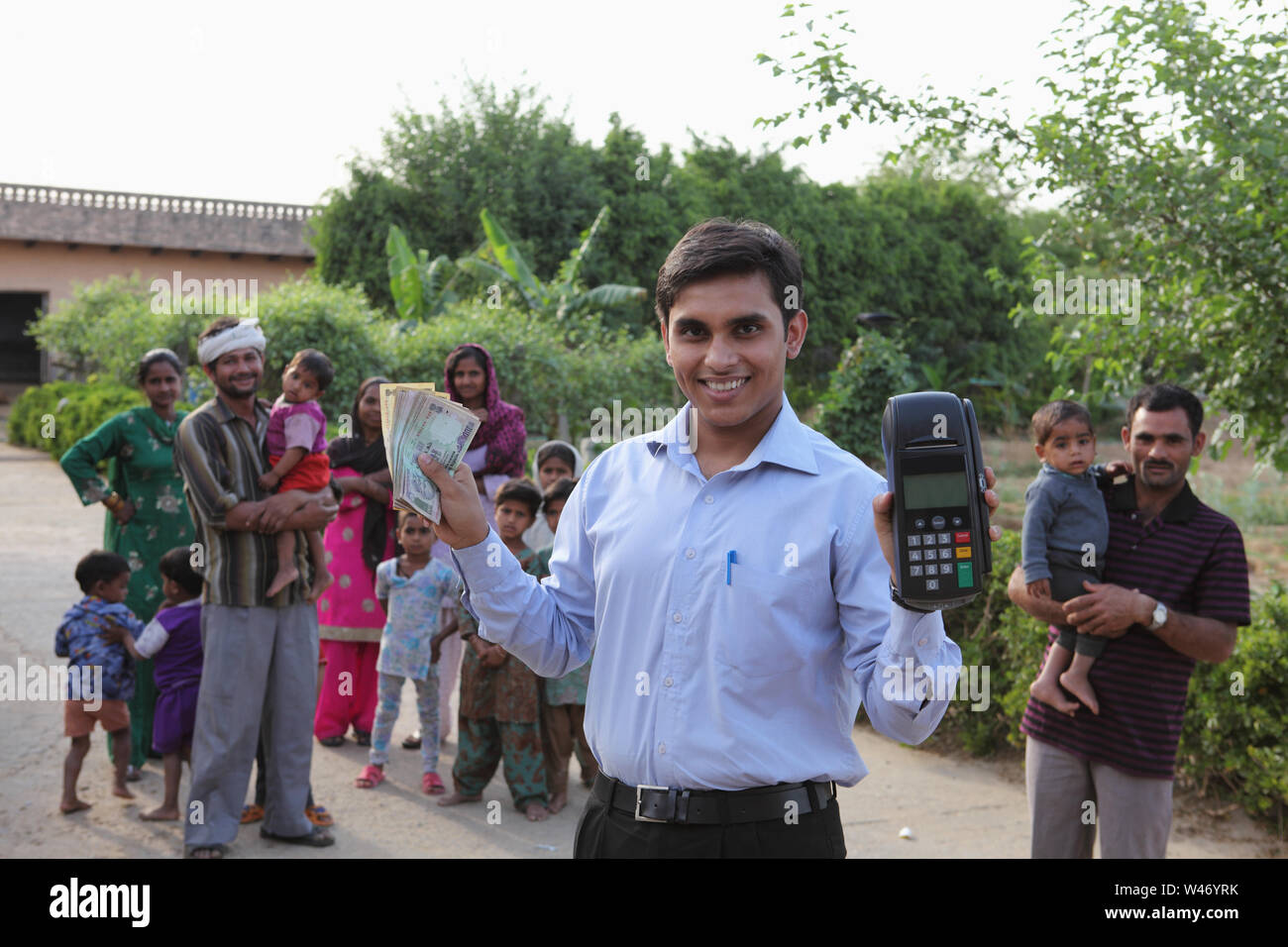 Portrait of a man showing money transfer machine with villagers ...