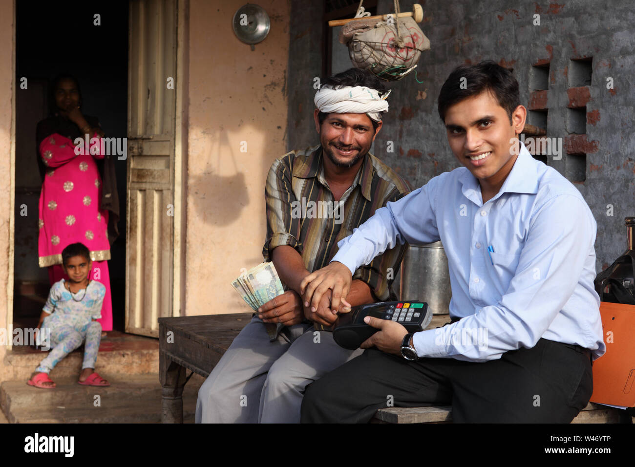 Executive taking thumb impression of a farmer on a money transfer ...