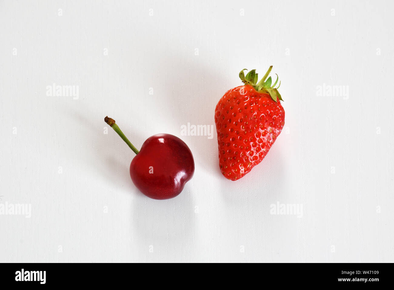 top view of a strawberry and one cherry on a white background Stock ...