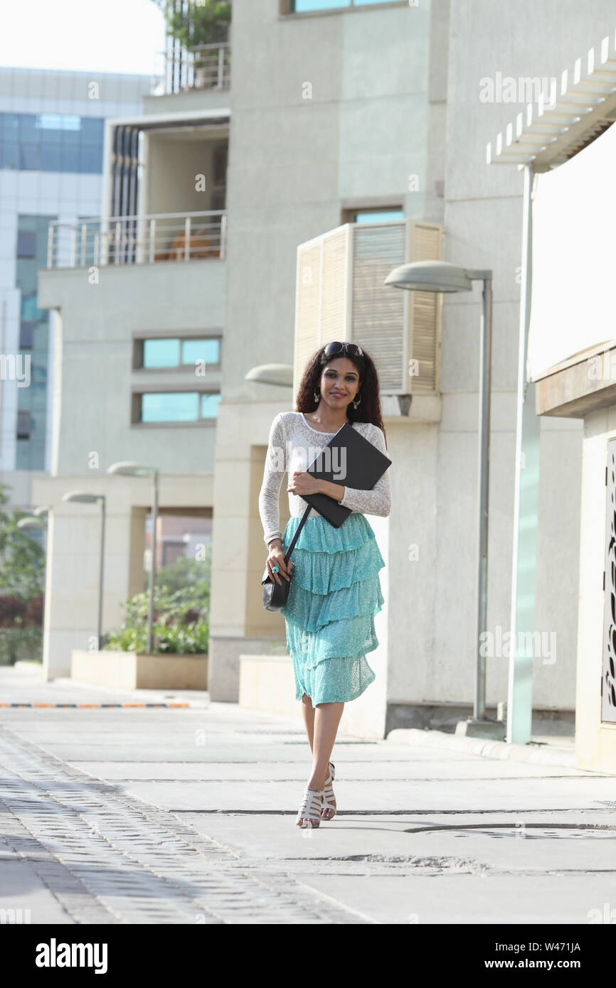 Businesswoman carrying laptop and walking Stock Photo - Alamy