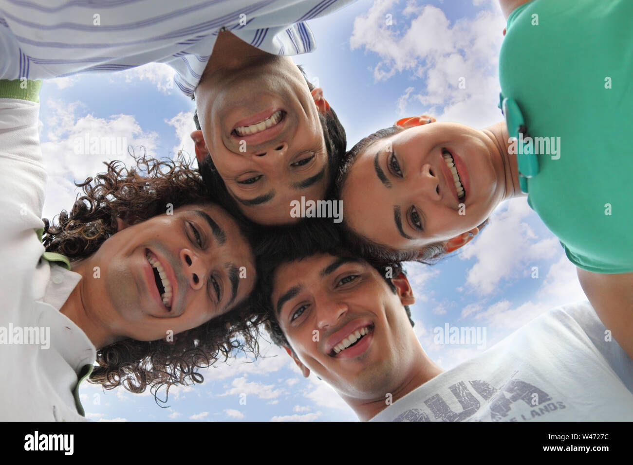 Group of friends in a huddle and smiling Stock Photo - Alamy