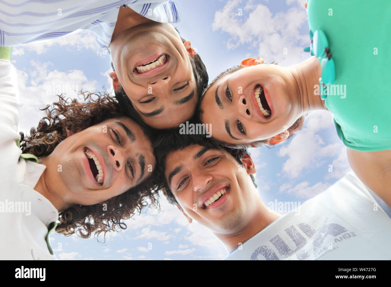 Group of friends in a huddle and smiling Stock Photo - Alamy