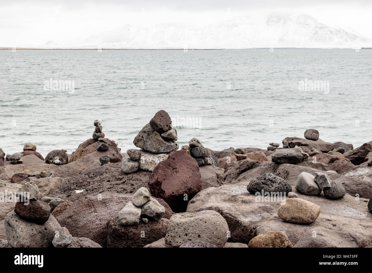 REYKJAVIK, ICELAND Rocks balanced on top of each other on the shoreline ...