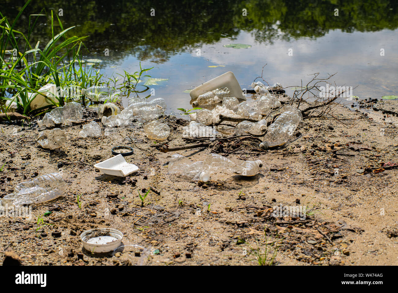 Trash and used plastic bottles in the river. Garbage near lake ...