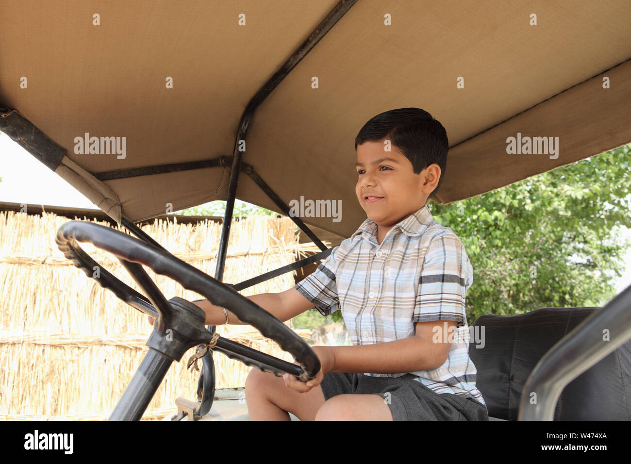 Boy driving a tractor Stock Photo - Alamy