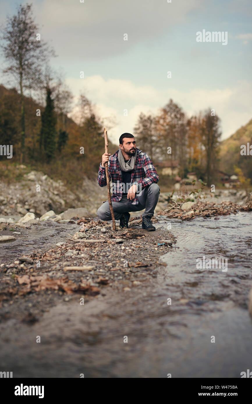 handsome man in nature, holding wooden stick Stock Photo - Alamy