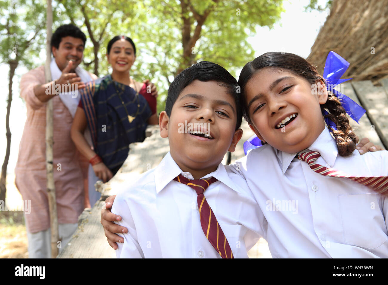 Portrait of school children smiling with their parents standing in the ...