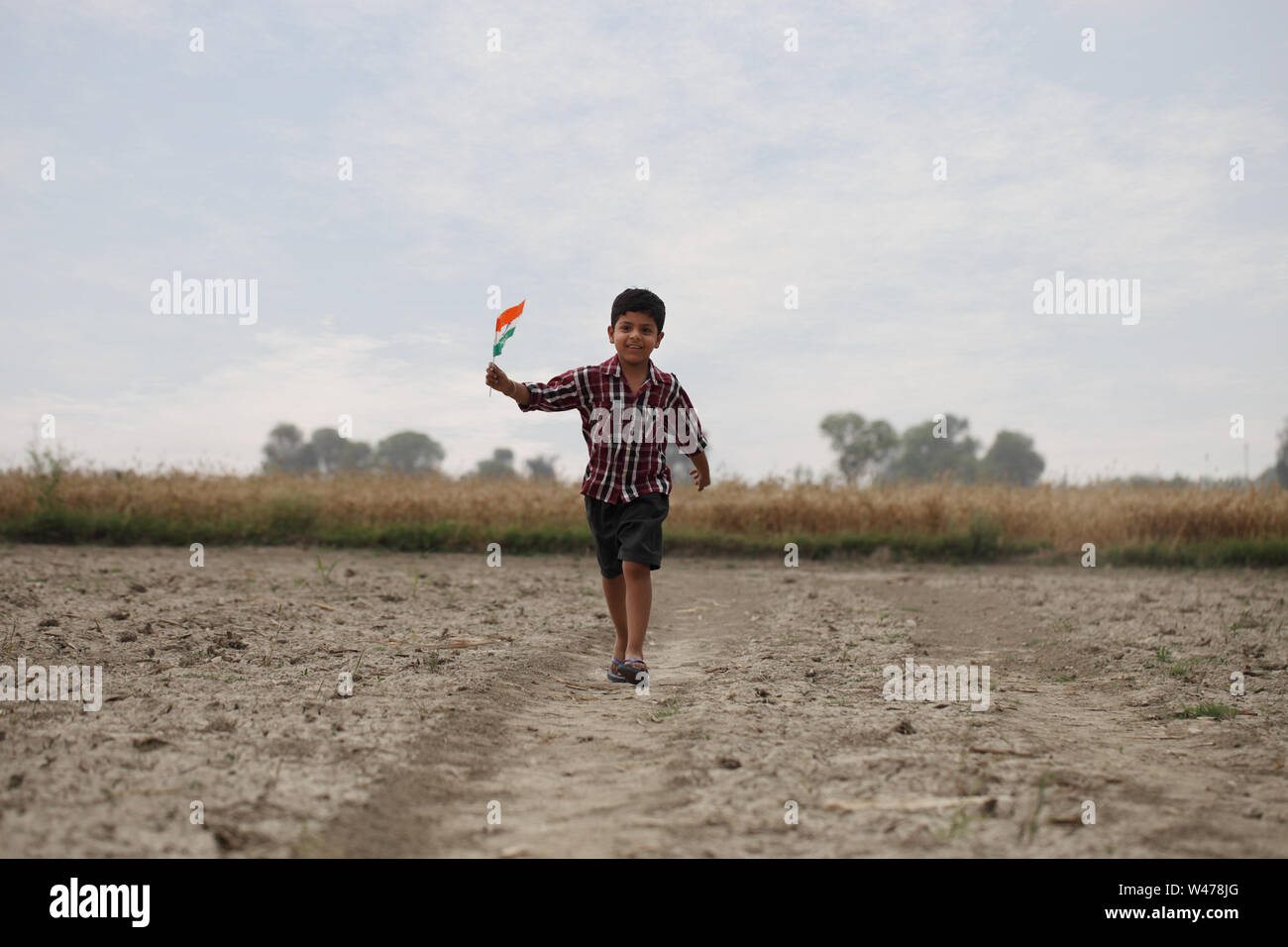 Boy running with Indian flag in a field Stock Photo - Alamy