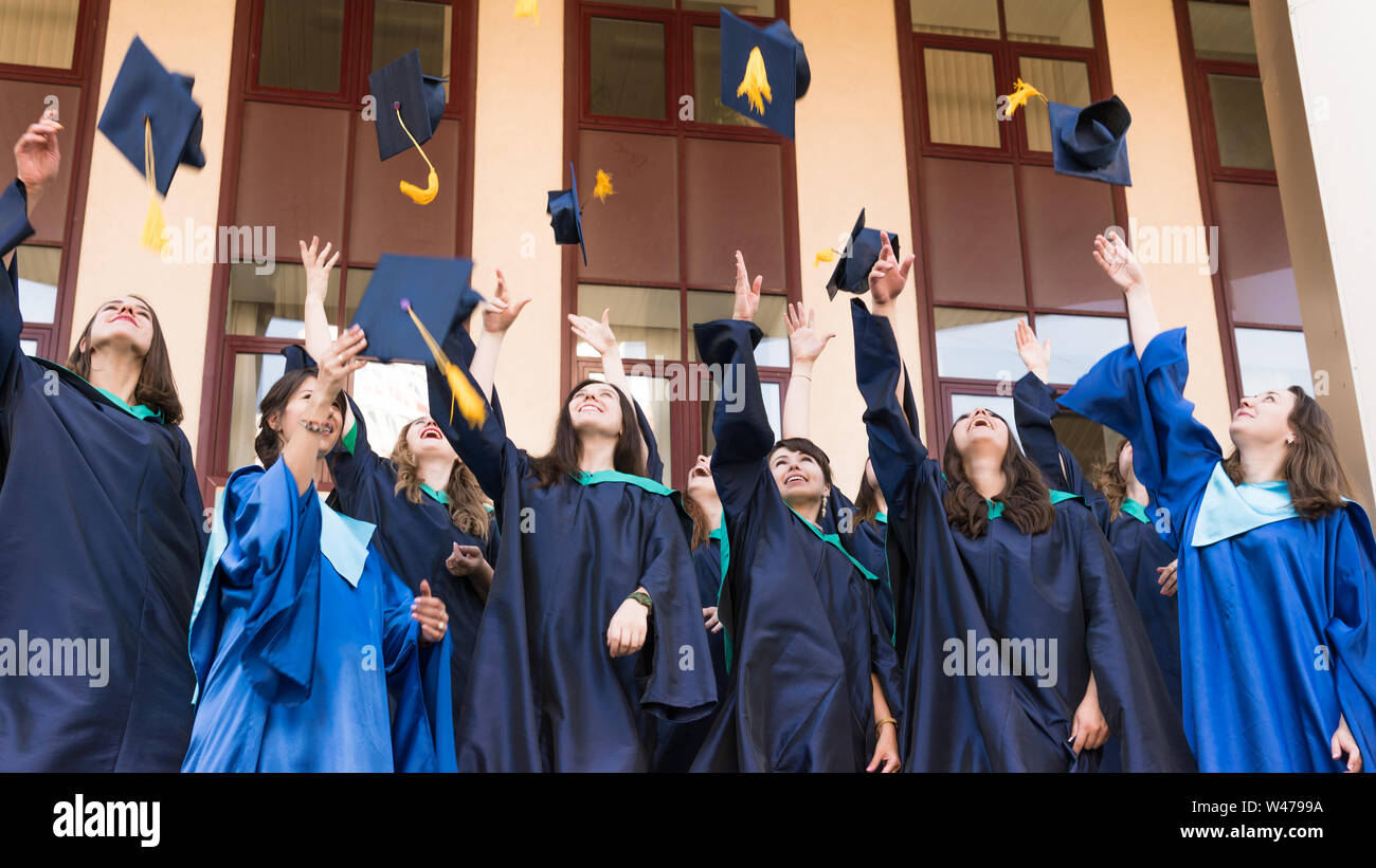 University graduates throwing graduation hats in the air. Group of ...