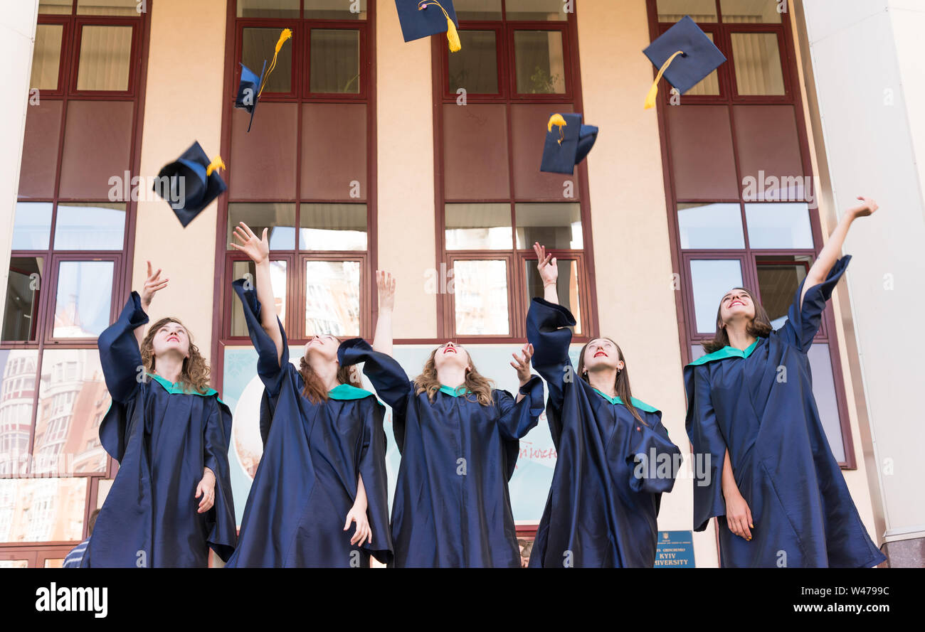 University graduates throwing graduation hats in the air. Group of ...