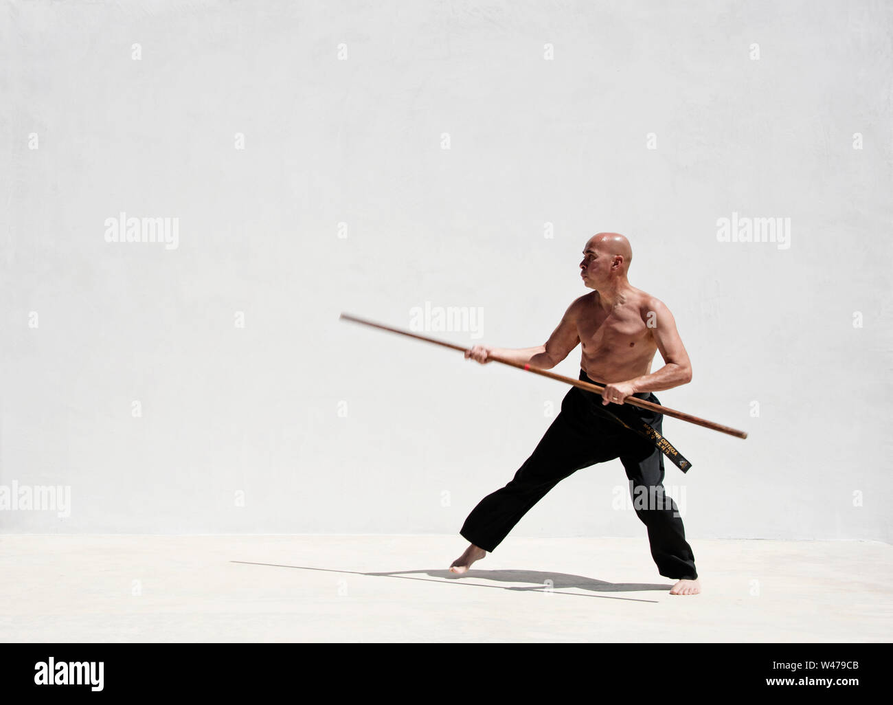 Black belt man practicing martial arts with a long stick Stock Photo ...