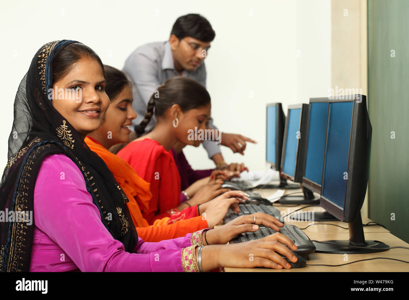 Women using computers with teacher assistance Stock Photo - Alamy