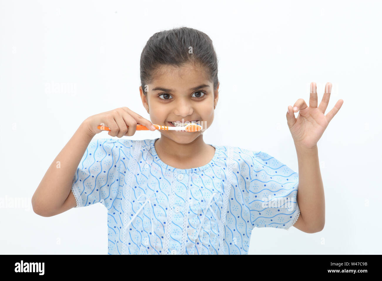 Girl brushing her teeth and showing OK sign Stock Photo - Alamy