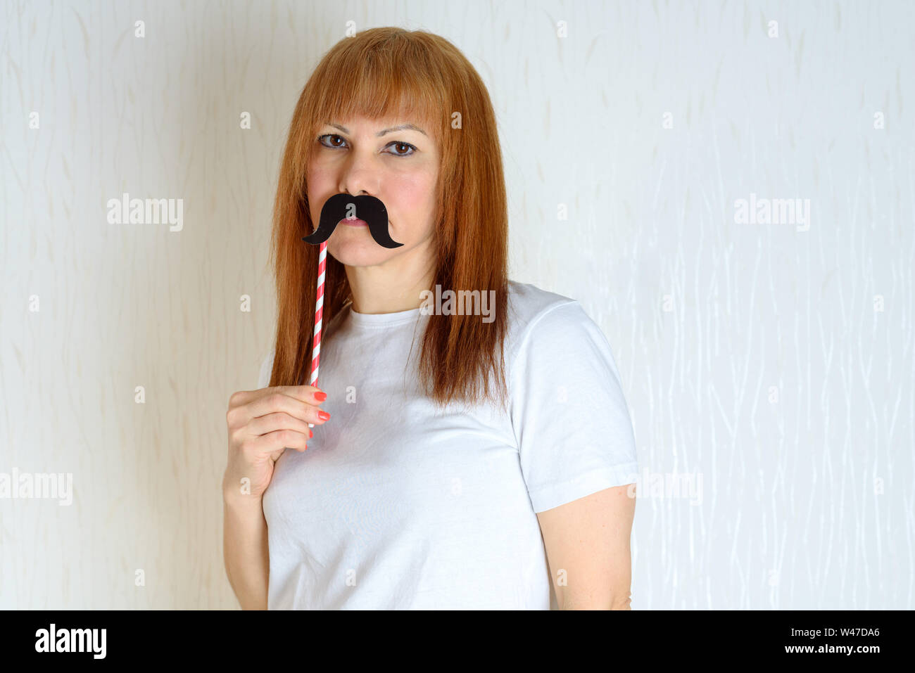 Attractive happy middle aged woman having fun with a fake moustache on ...