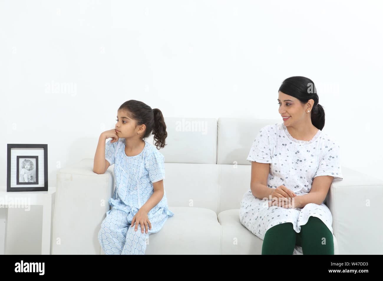Mother and daughter sitting at opposite ends of a couch Stock Photo - Alamy