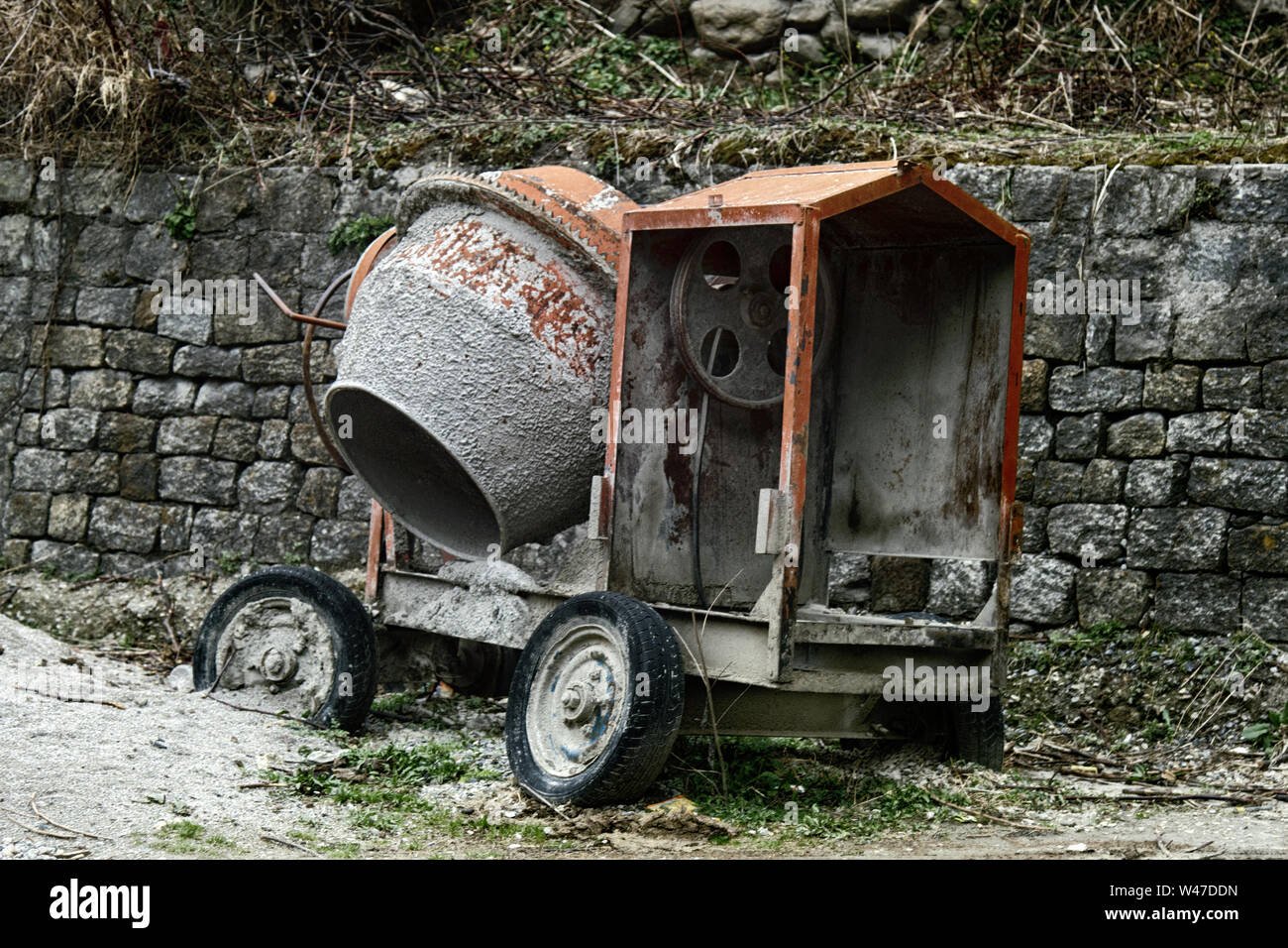 Concrete mixer abandoned near old brick wall Stock Photo - Alamy